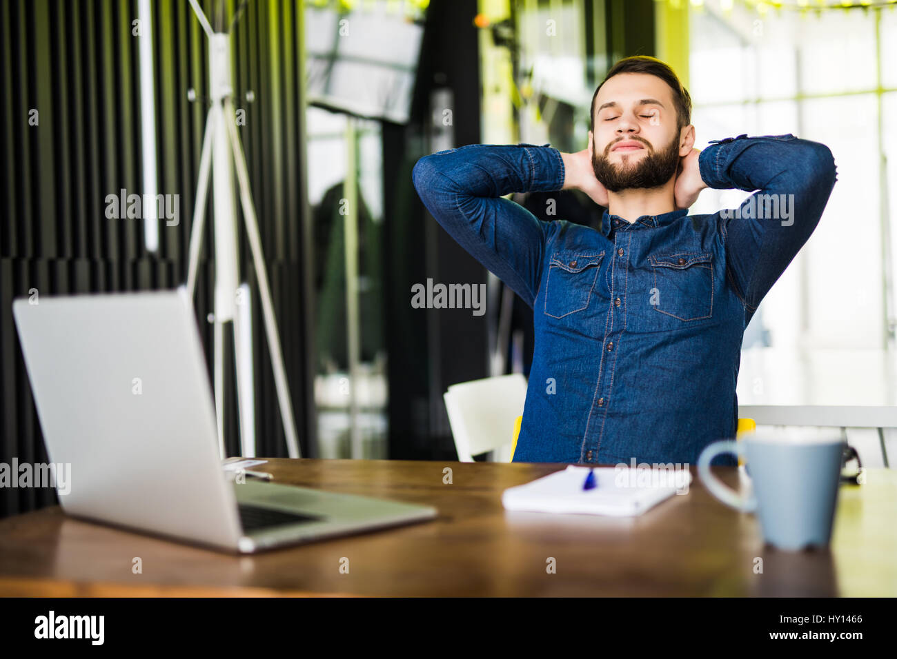 Young businessman relaxing at his desk in office Stock Photo - Alamy
