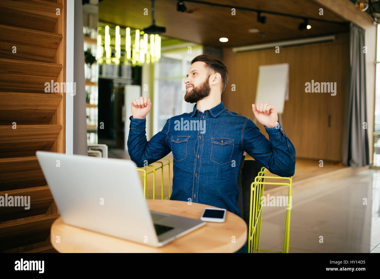 Happy excited young man sitting on workplace and celebrating success ...