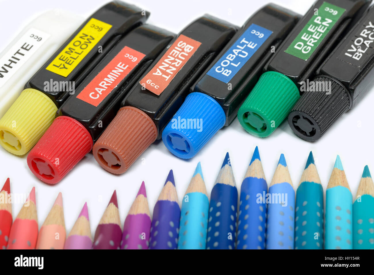 Bundle of colored pencils and tubes of paint on the colorful background ...