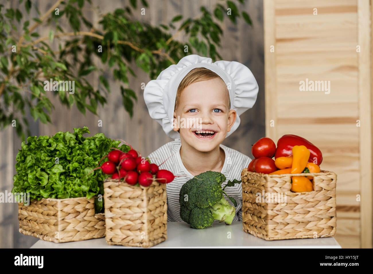 Handsome little kid in chef uniform with vegetables. Cooking in kitchen ...