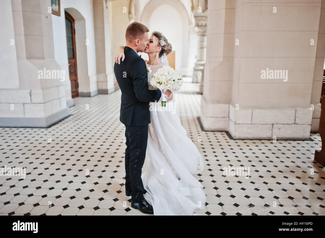 Photosession of stylish wedding couple on catholic church Stock Photo ...
