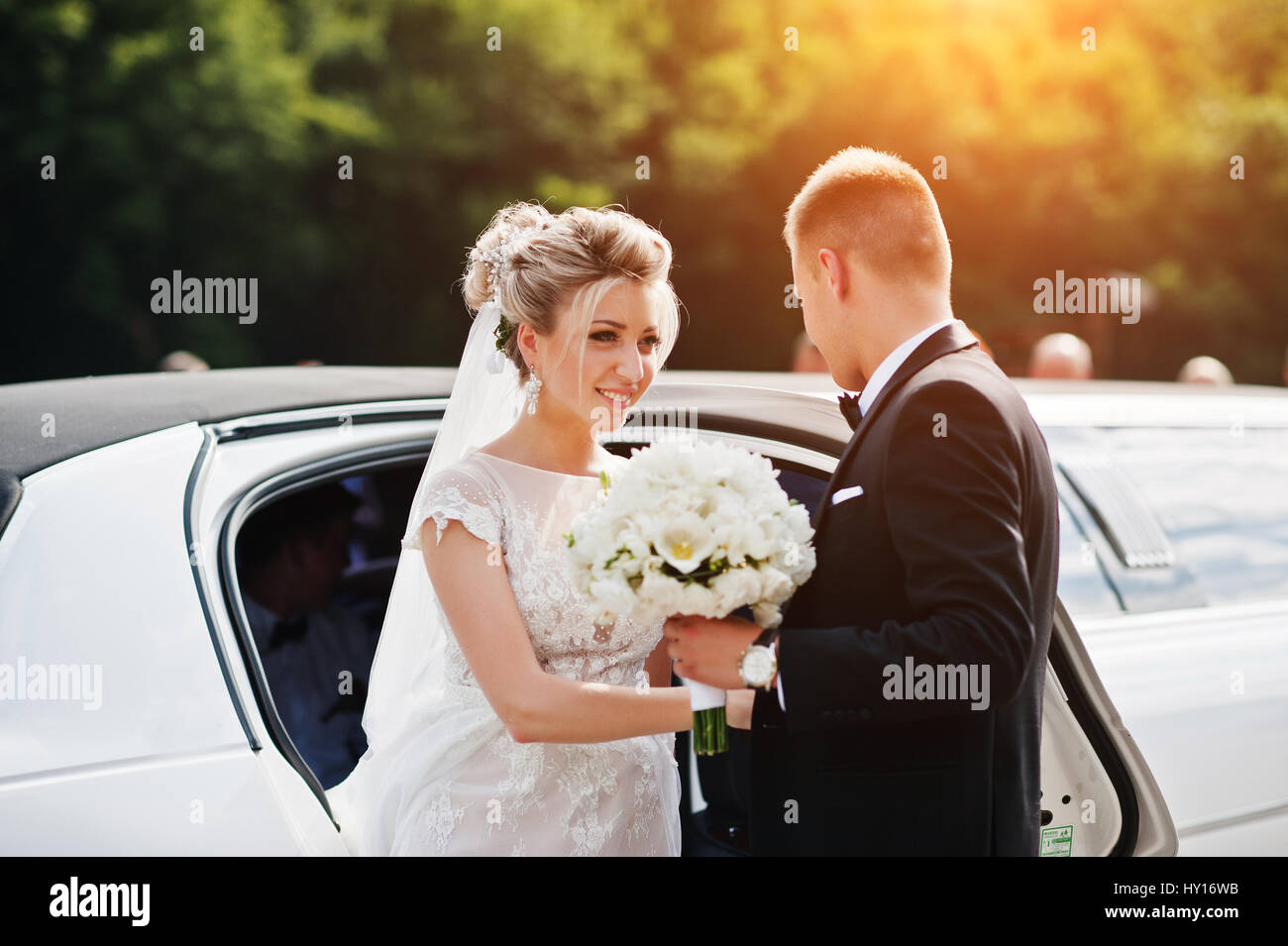 Groom give his hand for bride to take from limousine at wedding day ...