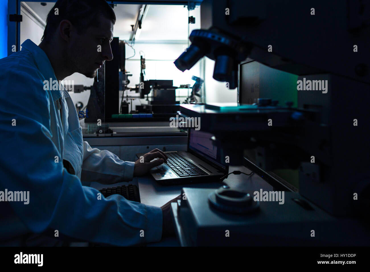Silhouette of a scientist looking into microscope in a chemistry ...