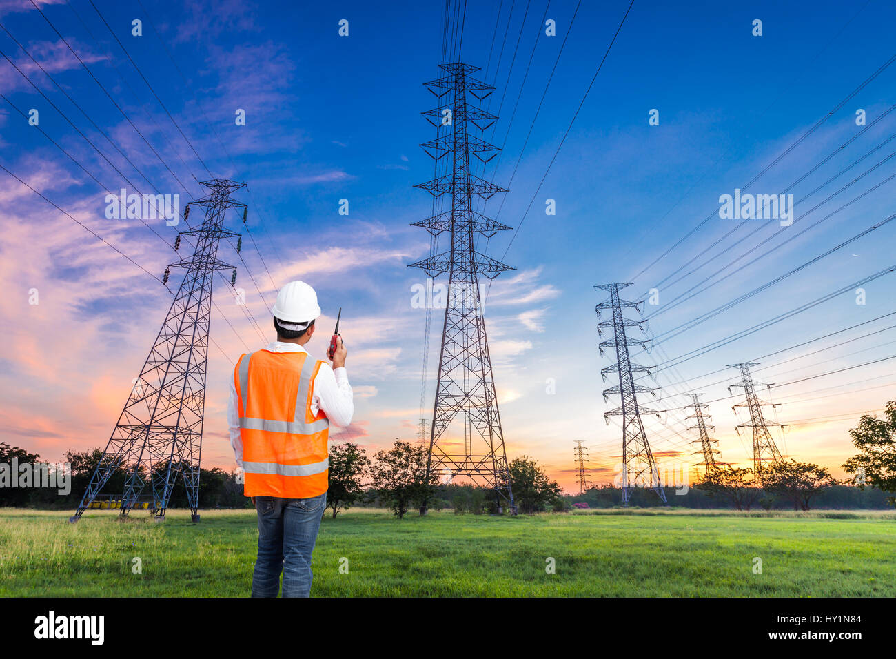 Electrical engineer with high voltage electricity pylon at sunrise ...