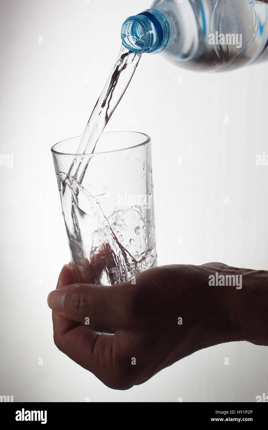 Hand, glass , bottle and pouring water Stock Photo - Alamy