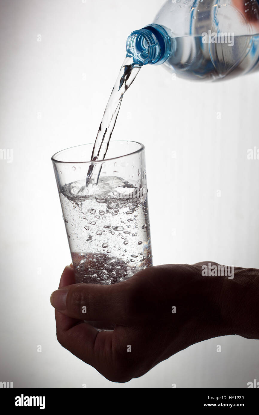 Hand, glass , bottle and pouring water Stock Photo - Alamy
