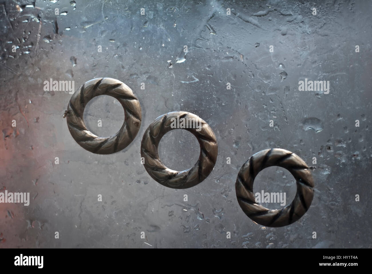 Three brass rings on the wet glass Stock Photo - Alamy