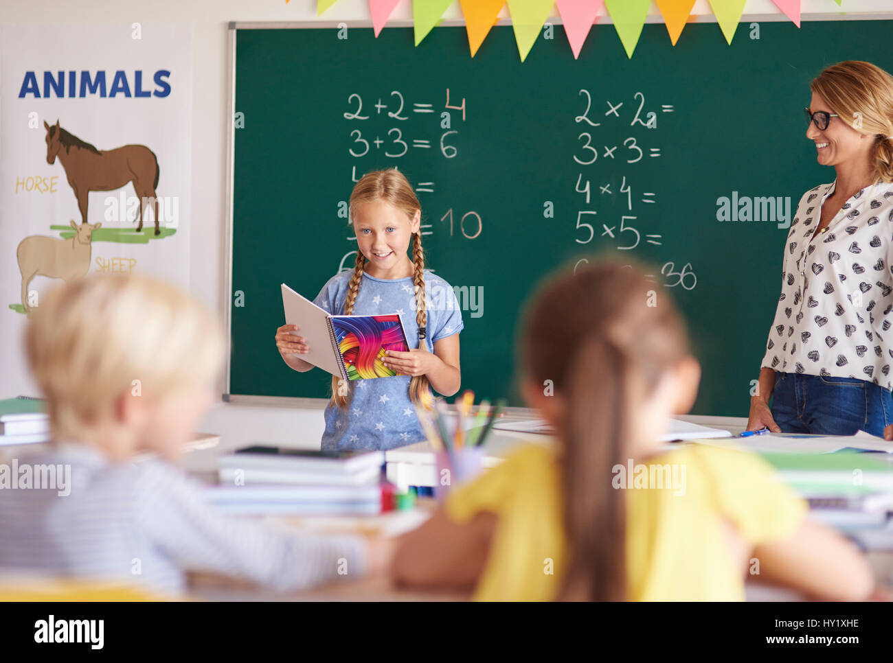 Little girl reading homework in the classroom Stock Photo - Alamy
