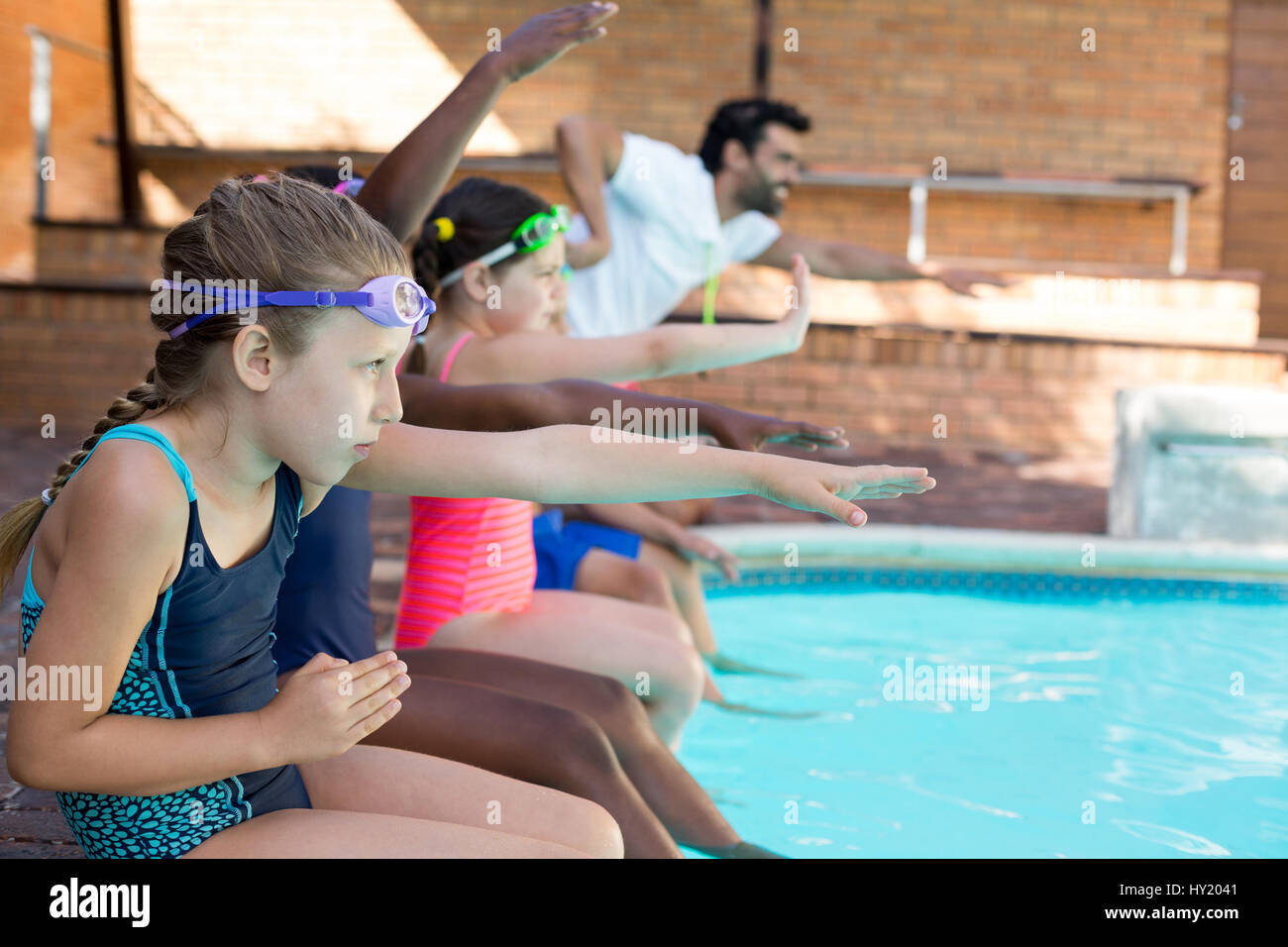 Male swimming instructor assisting girls at poolside Stock Photo - Alamy