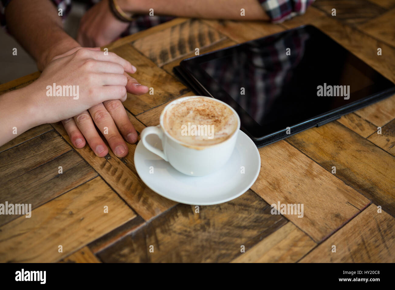 Cropped image of couple holding hands with coffee cup and tablet PC on ...