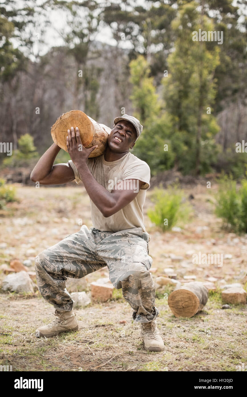 Military soldier carrying a tree log during obstacle course in boot ...