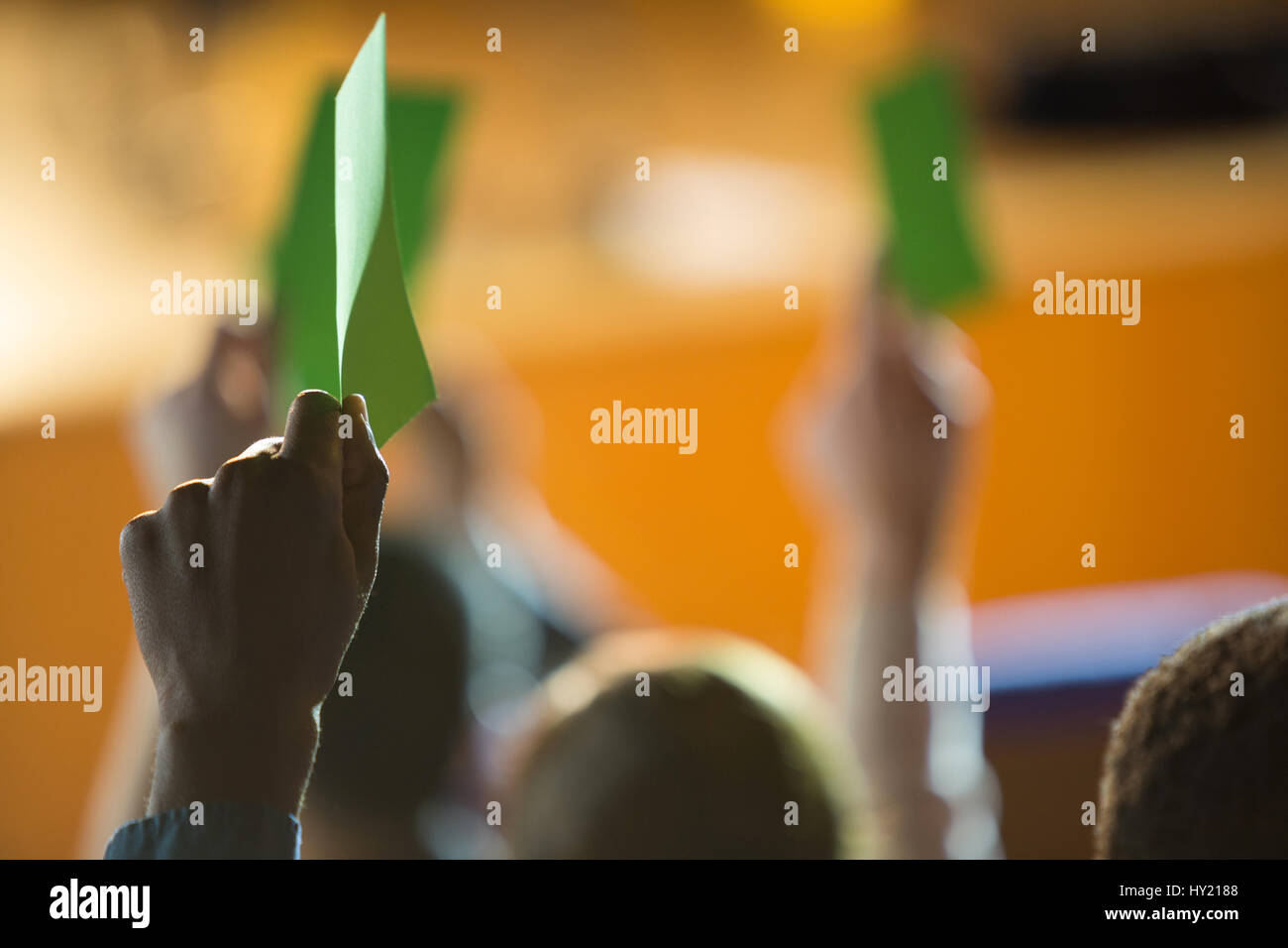 Rear view of business executives show their approval by raising hands ...