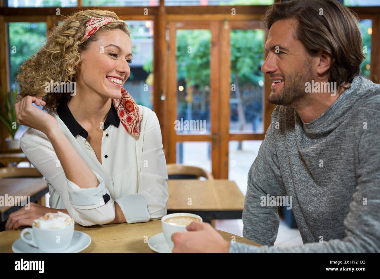 Smiling young couple talking at table in cafeteria Stock Photo - Alamy