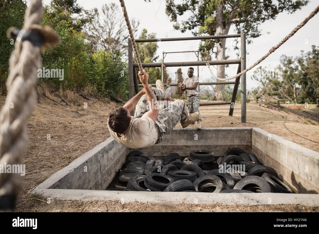 Young military soldiers practicing rope climbing during obstacle course ...