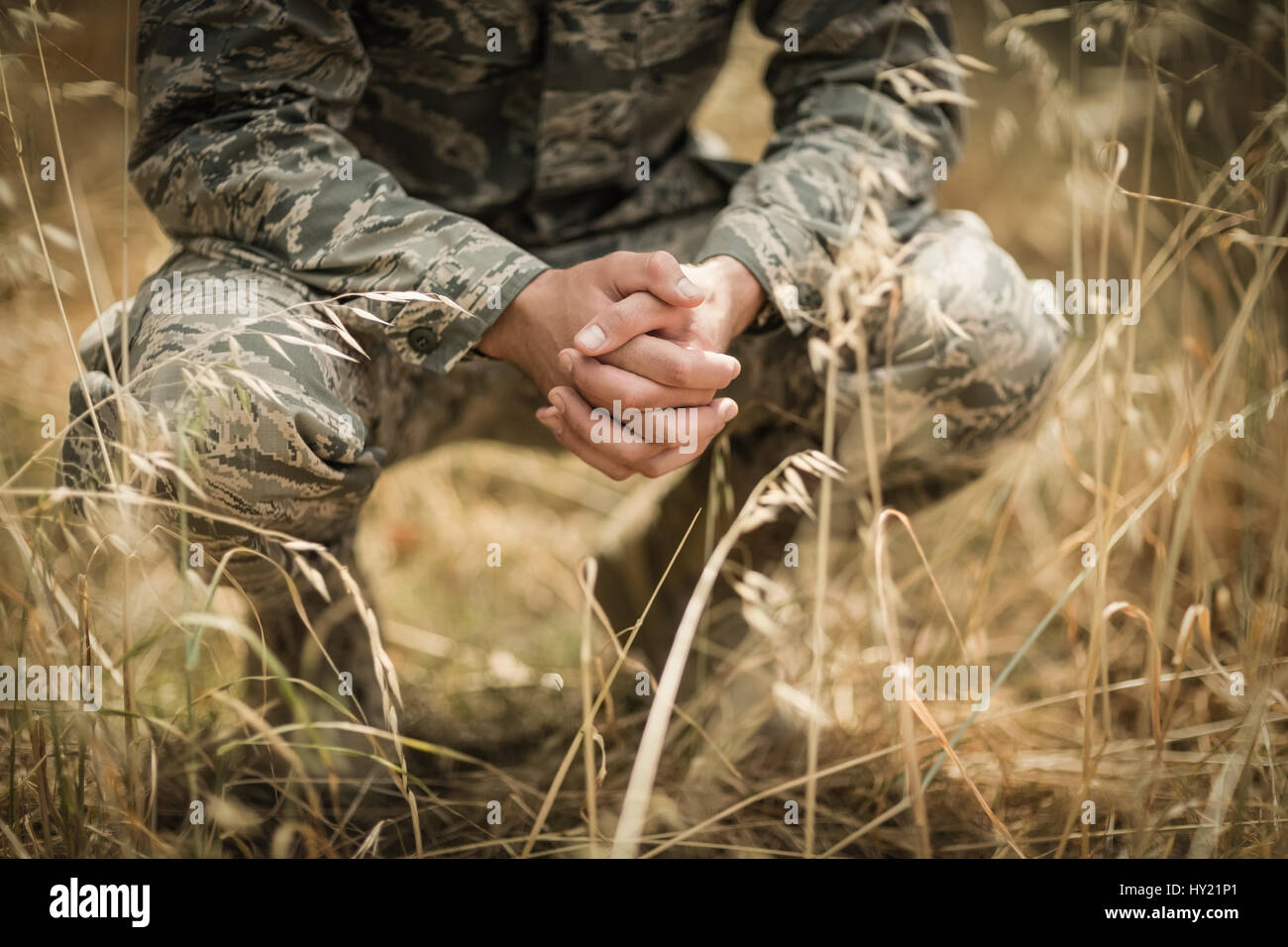 Military soldier crouching in grass in boot camp Stock Photo - Alamy
