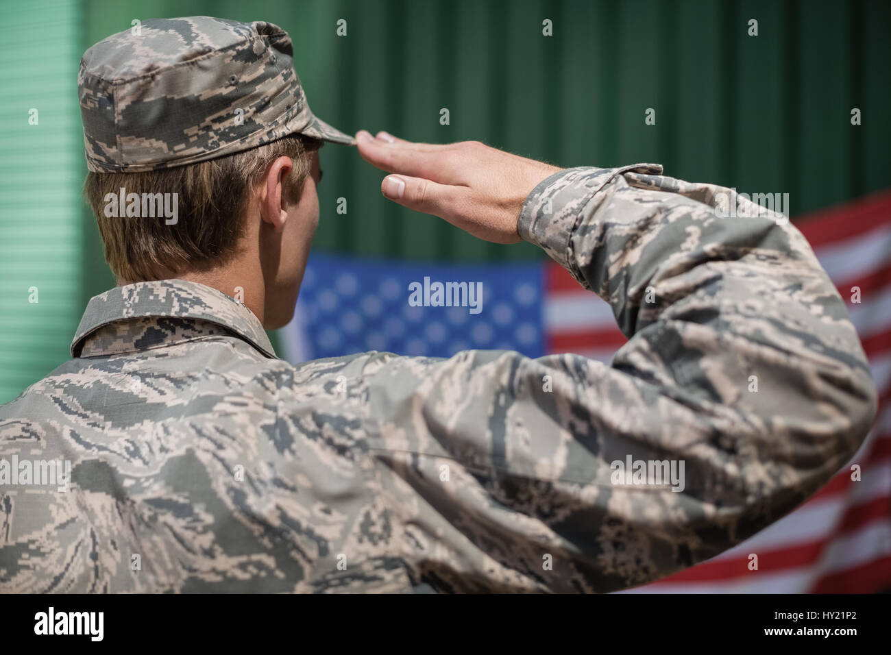 Rear view of military soldier giving salute to american flag in boot ...