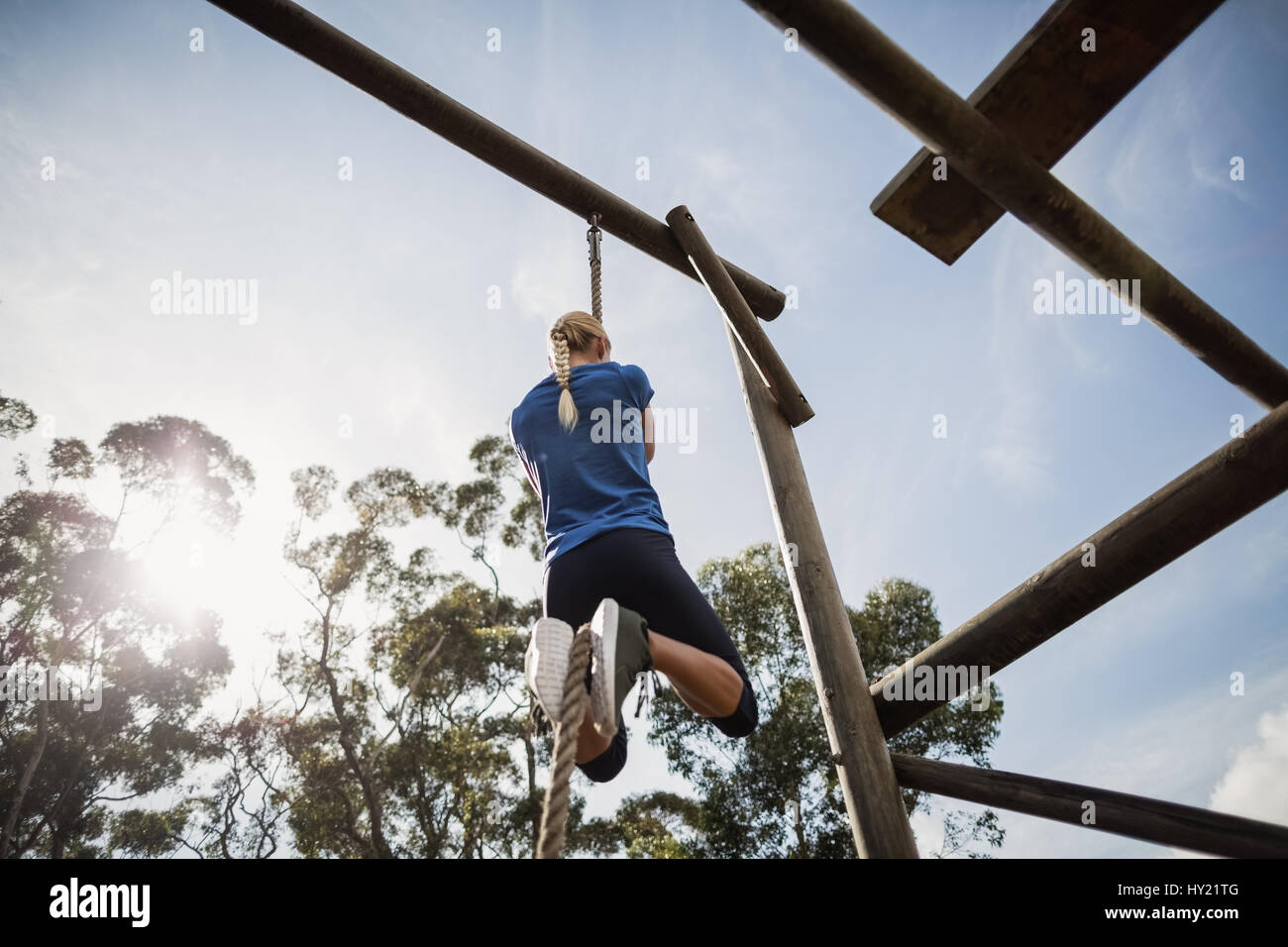 Fit woman climbing down the rope during obstacle course in boot camp ...