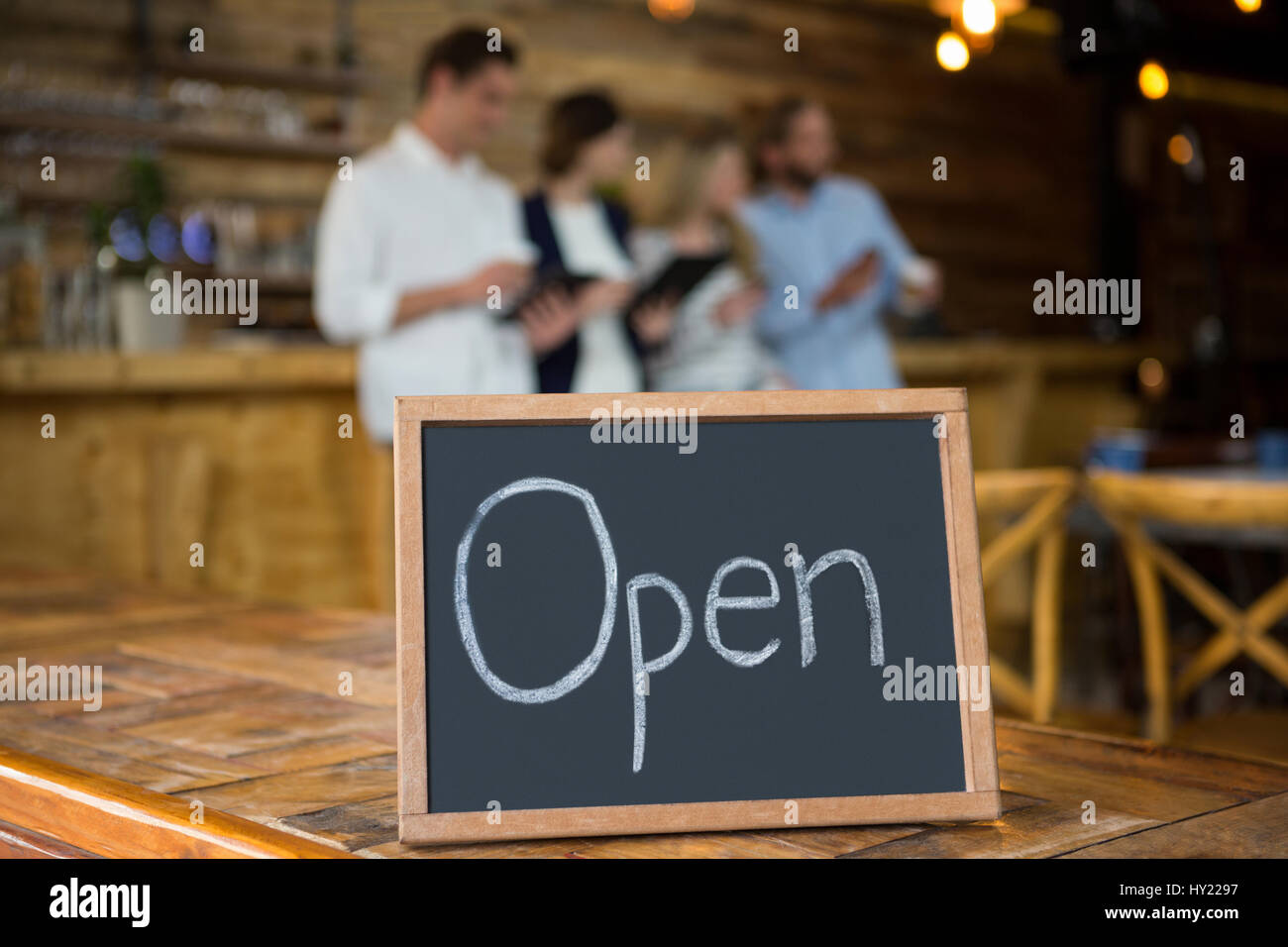 Open signboard on table with customers in background at coffee shop ...