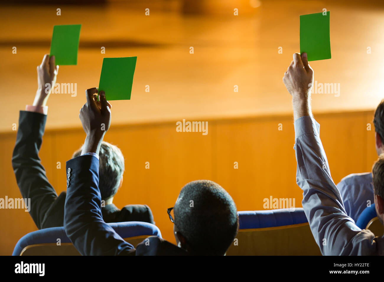 Rear view of business executives show their approval by raising hands ...
