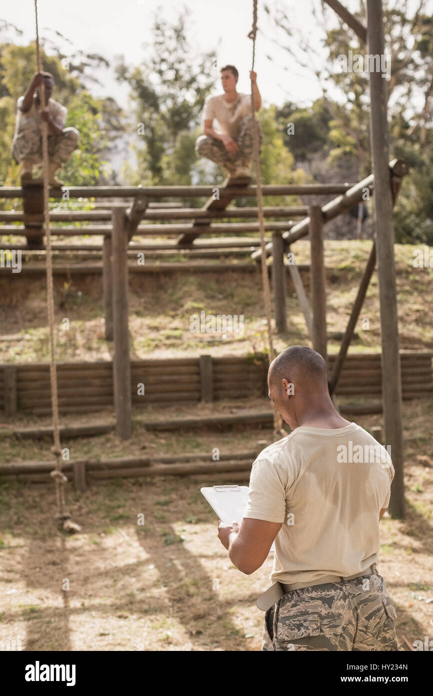 Military soldiers climbing rope during obstacle course training at boot ...