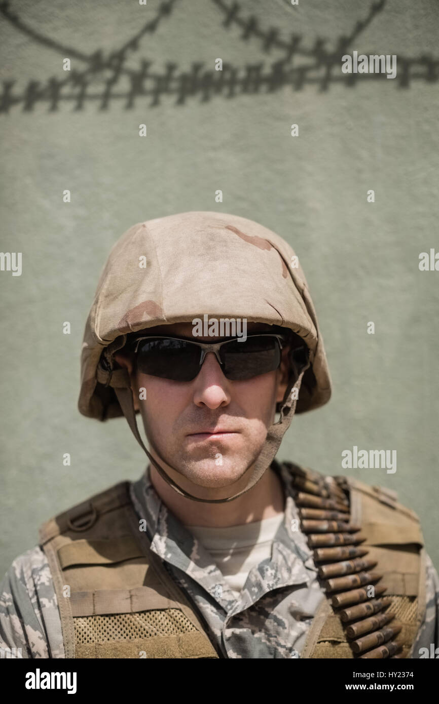 Close-up of confident military soldier standing against concrete wall ...