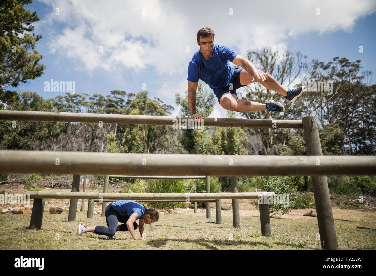 Man and woman jumping over the hurdles during obstacle course in boot ...
