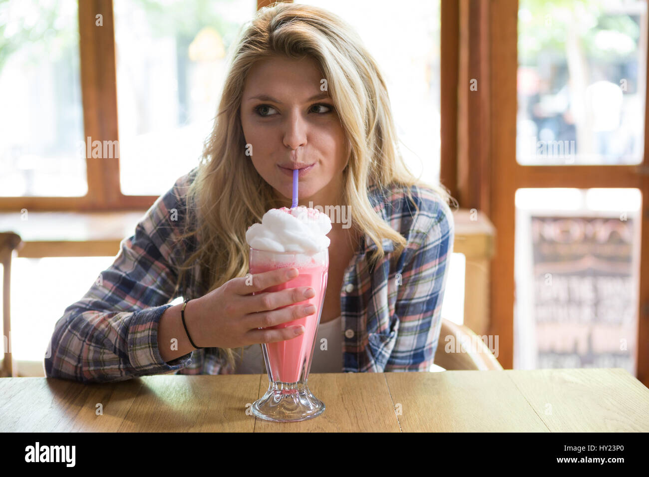 Beautiful young woman having milkshake at table in coffee shop Stock ...