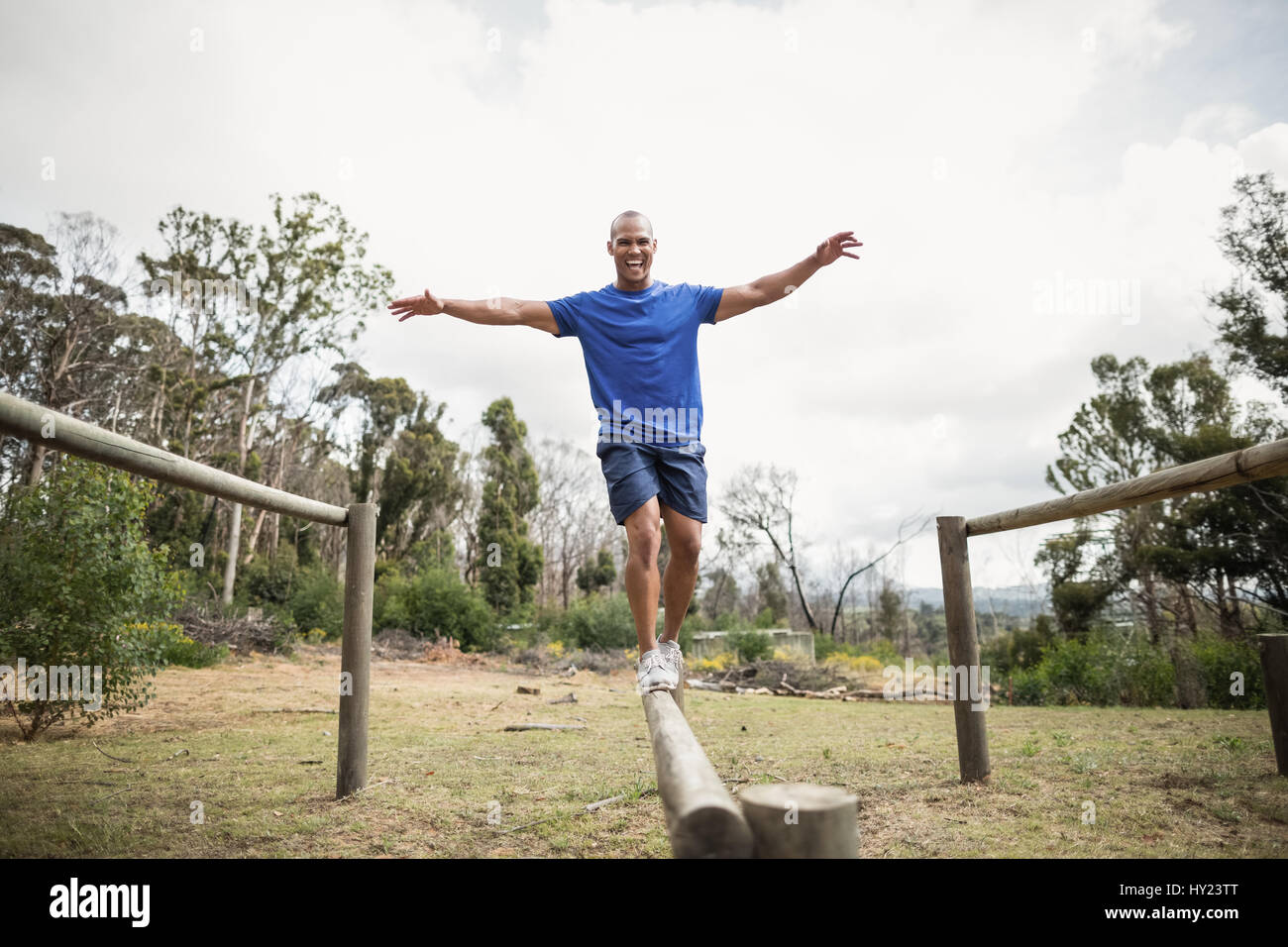 Fit man balancing on hurdles during obstacle course training at boot ...