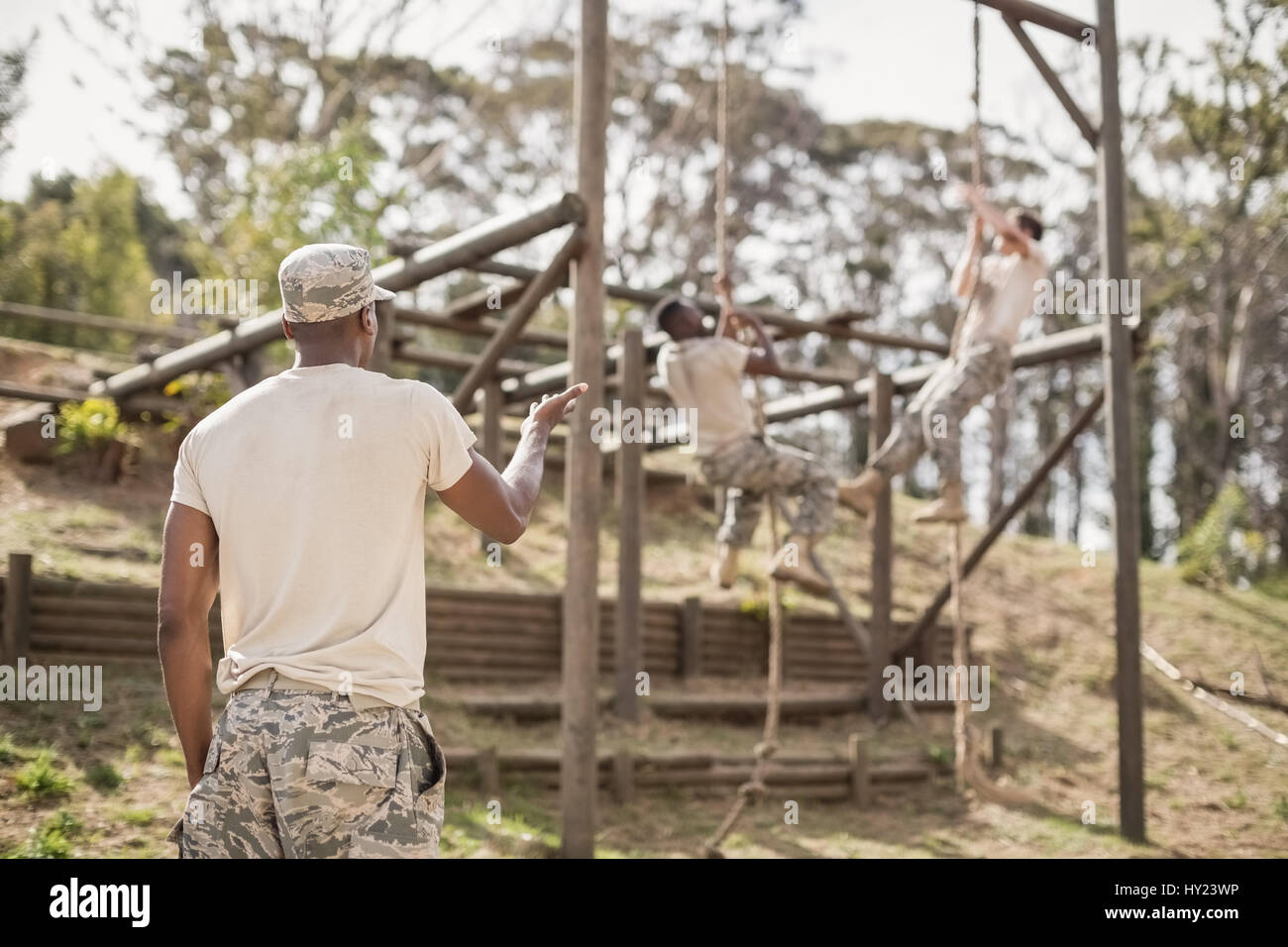 Military soldiers climbing rope during obstacle course training at boot ...