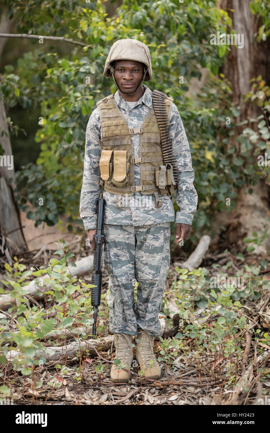 Portrait of confident military soldier standing with rifle in boot camp ...