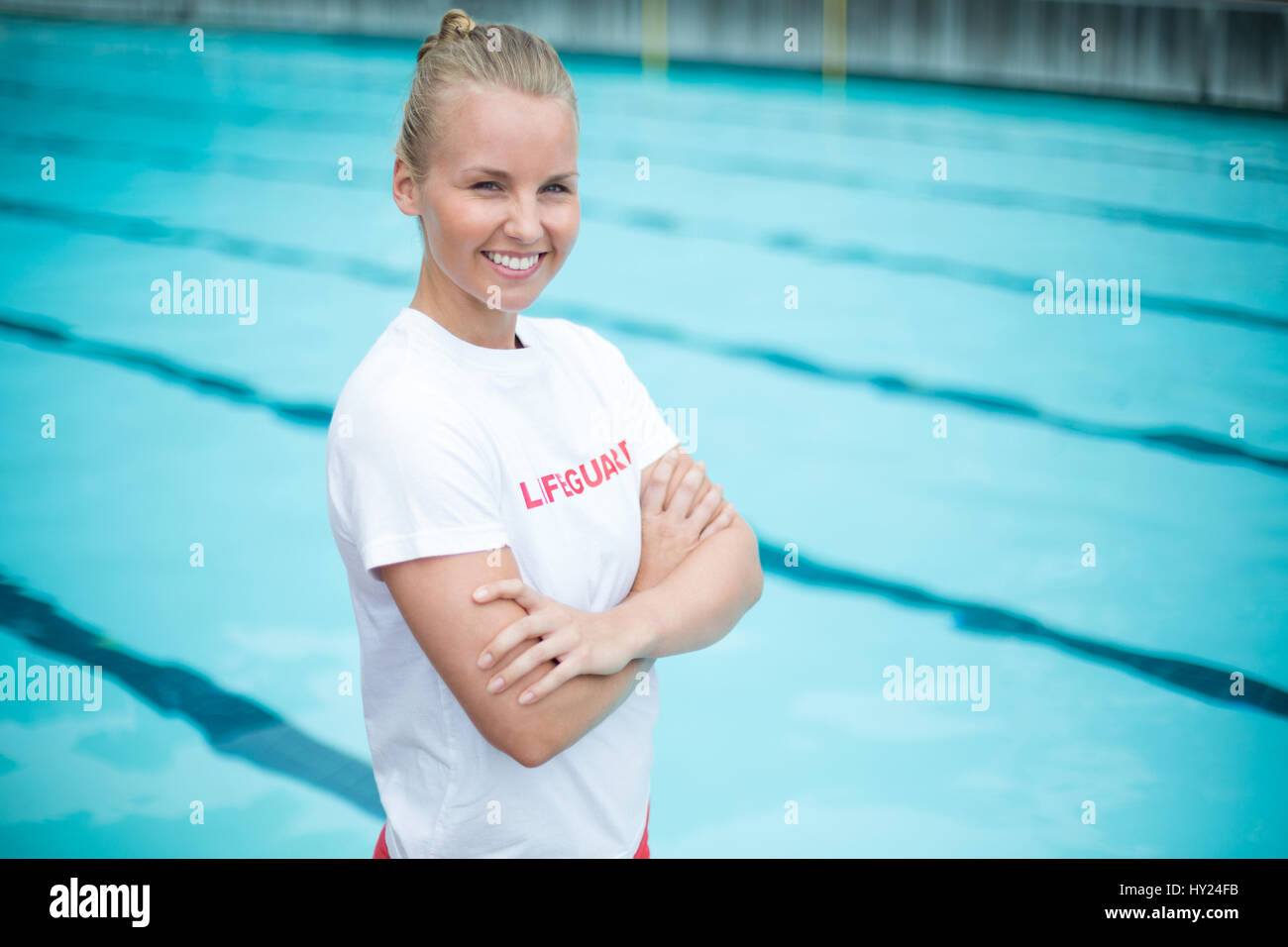 Portrait of happy female lifeguard standing at poolside Stock Photo - Alamy