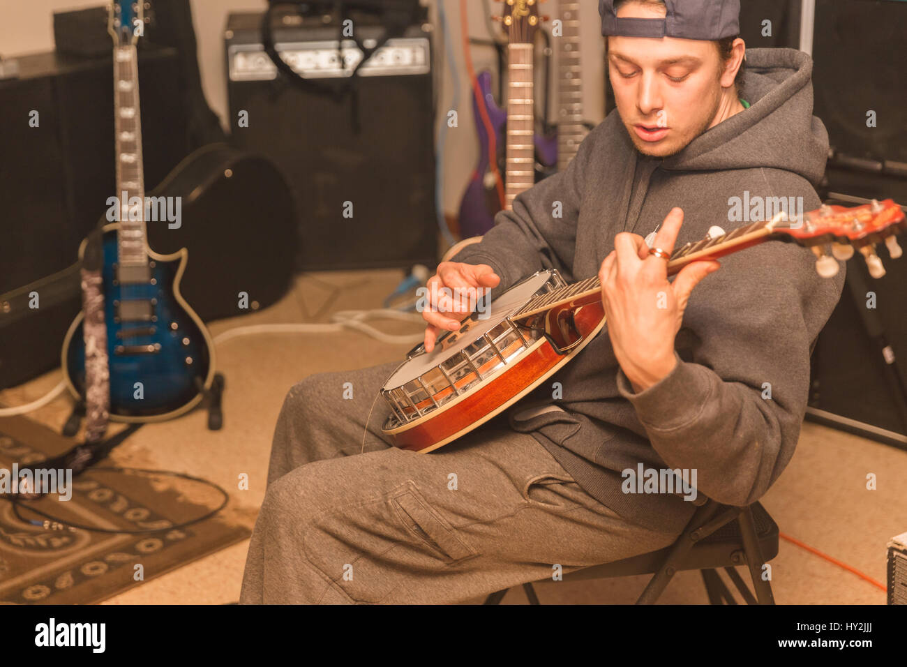 Man playing banjo in a recording space or jam room Stock Photo - Alamy