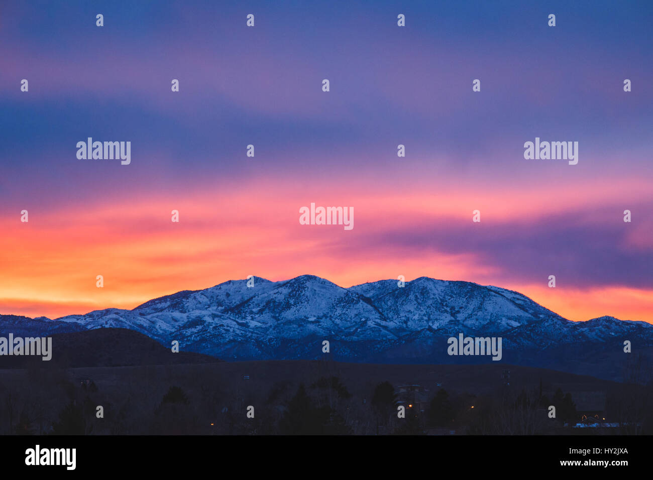 Bright orange and dark purple sky over snowy mountains in Utah. Near ...