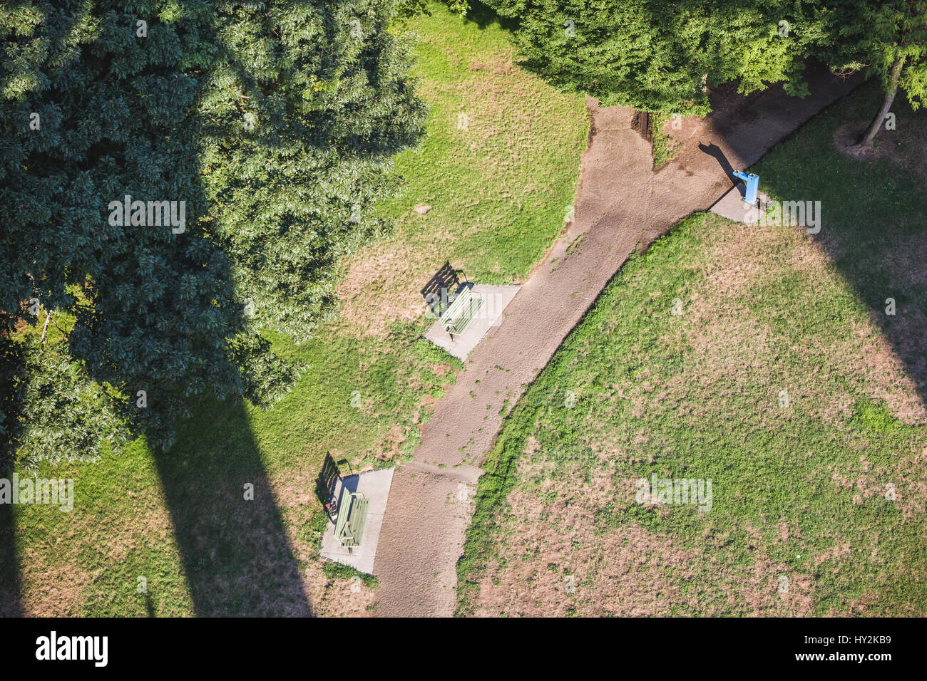 Park benches viewed from above on a tall bridge. Long shadows stretch ...