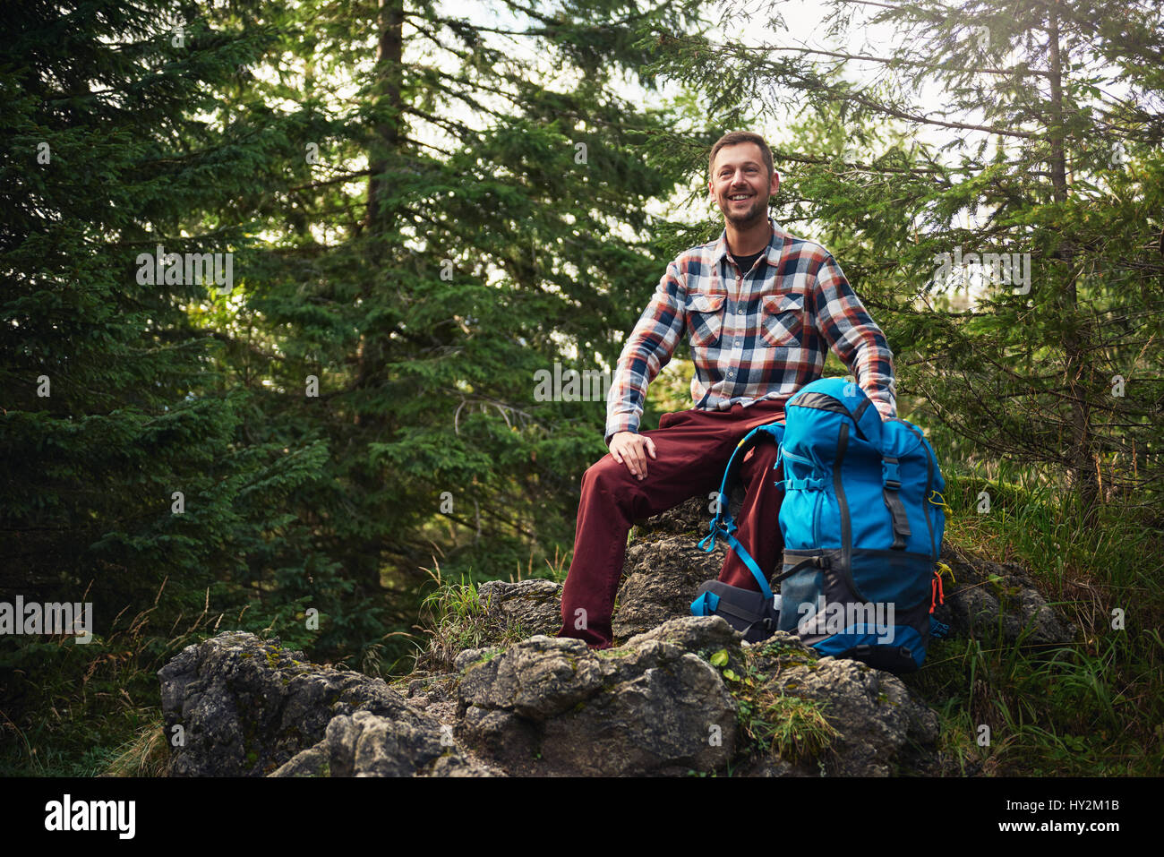 Smiling hiker sitting on a rock in the woods Stock Photo - Alamy