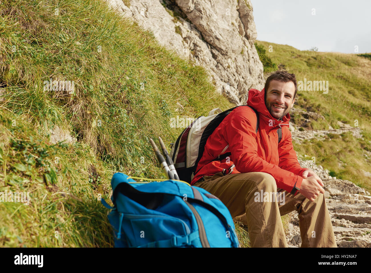 Smiling hiker sitting on a trail in the mountains Stock Photo - Alamy