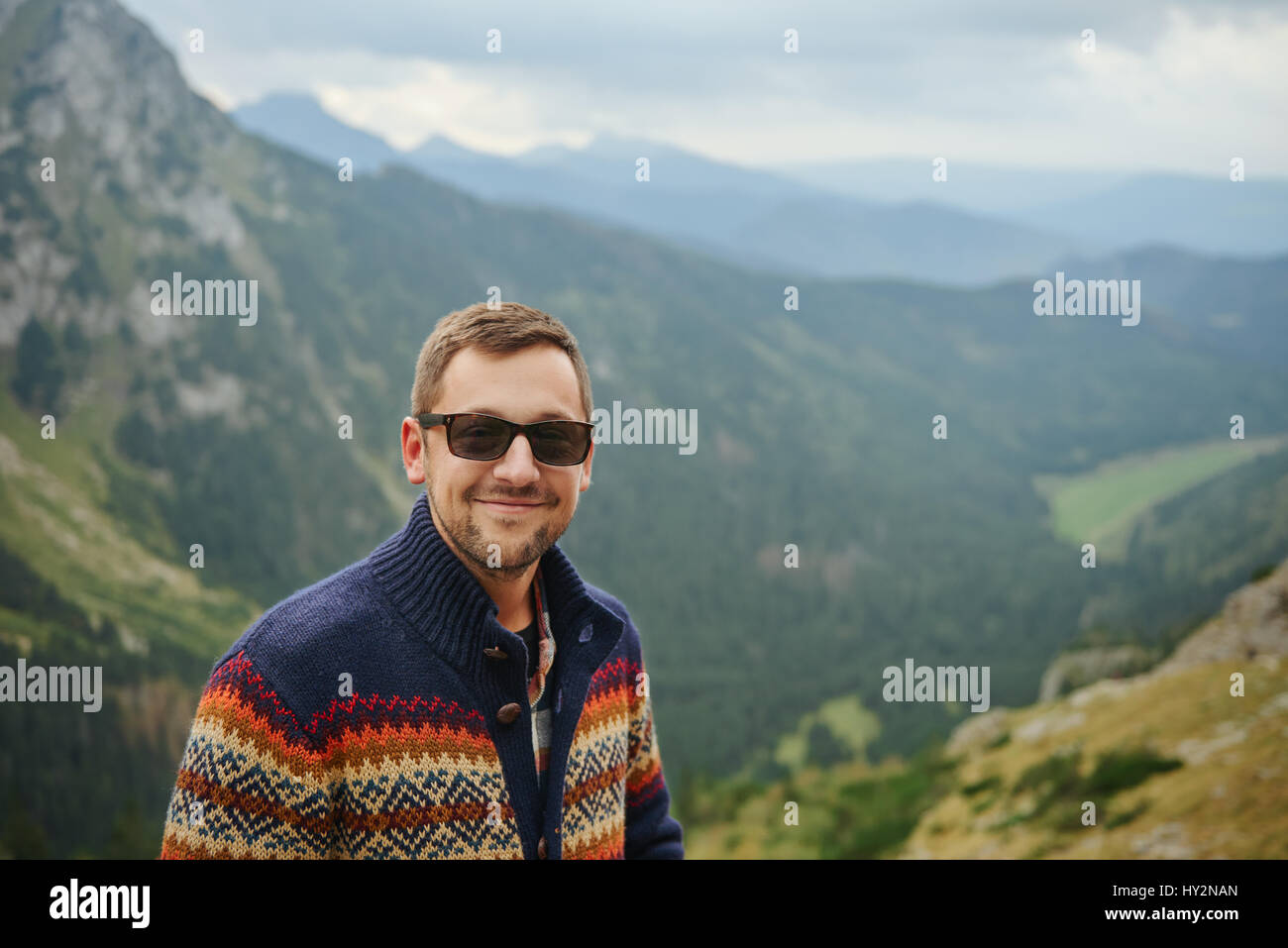 Smiling hiker standing in front of a majestic mountain landscape Stock ...