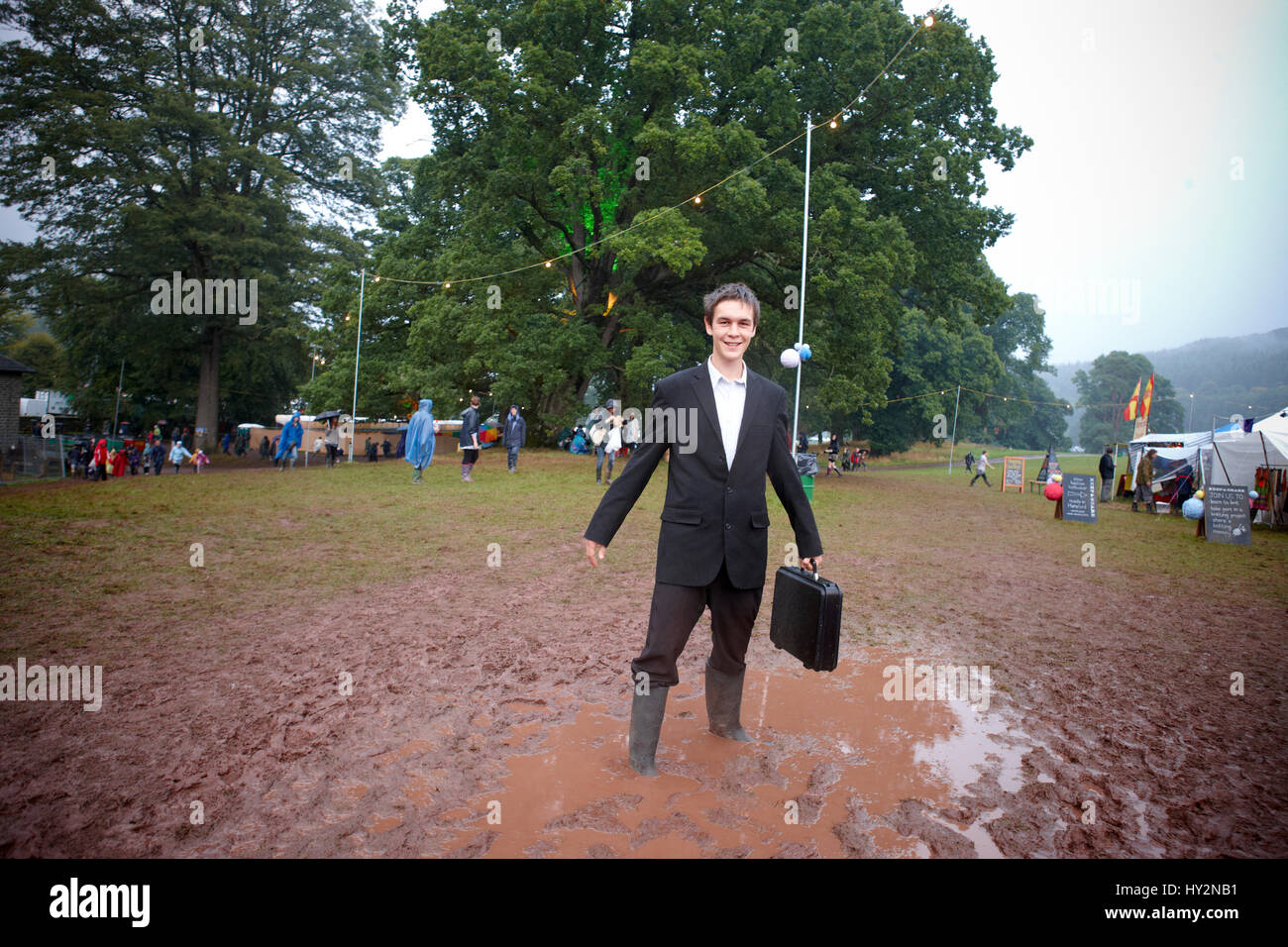 Man wearing a black suit holding a brief case standing in a puddle of ...