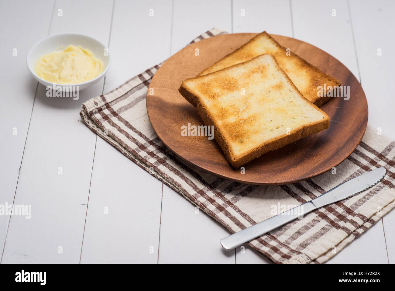Close-up of slice of toast bread with butter on wood table Stock Photo ...