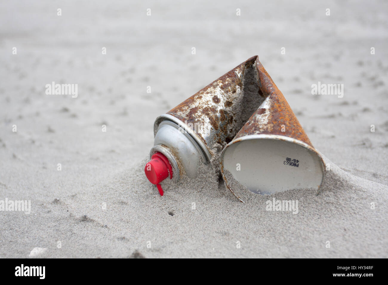 An old rusty aluminium aerosol spray can littering a sandy beach ...