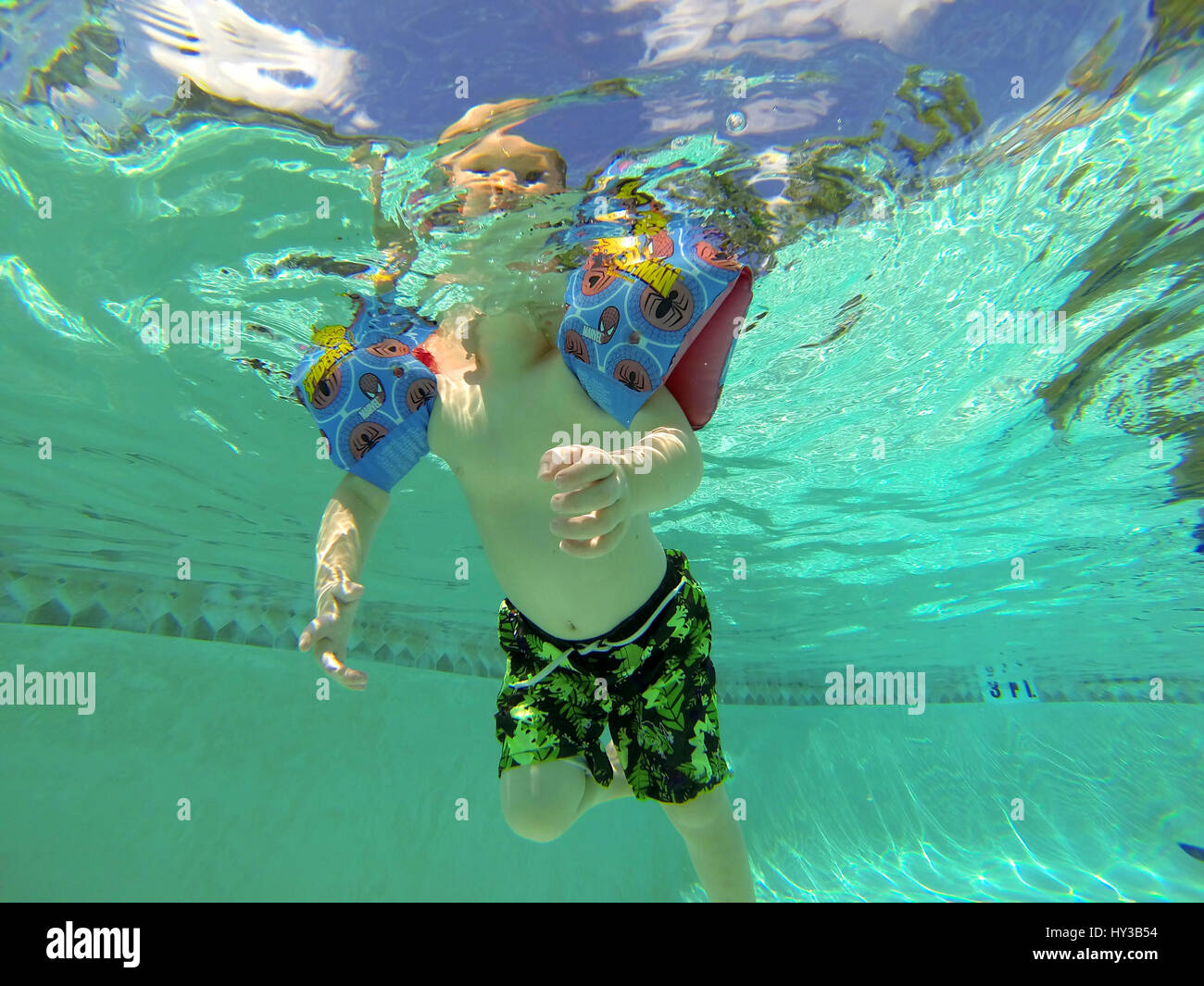 underwater in pool looking up boy swims over top Stock Photo - Alamy