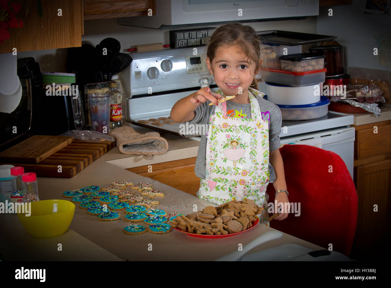 little girl making Christmas cookies with apron holding up cookie Stock ...