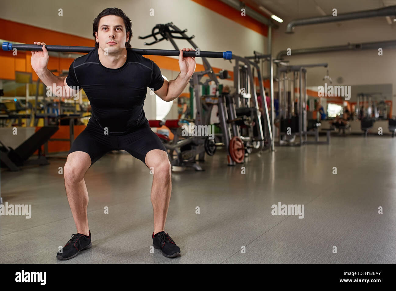 young man in the black sportwear with bar flexing muscles in gym. sport ...