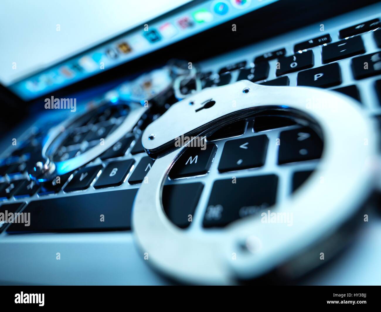 A set of handcuffs on a laptop computer to illustrate cyber crime Stock ...