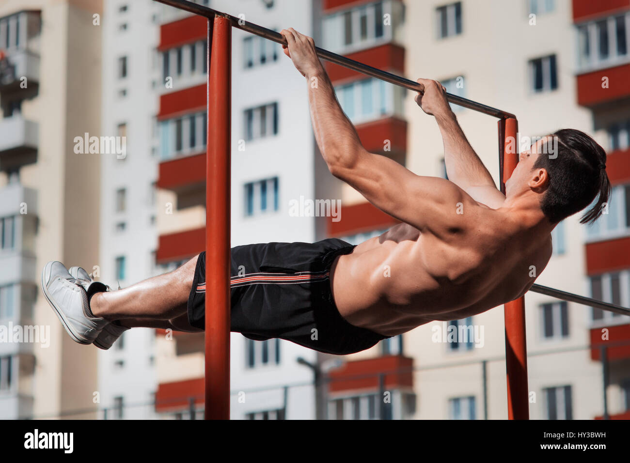 Fit young man doing push ups on horizontal bar outdoors Stock Photo - Alamy