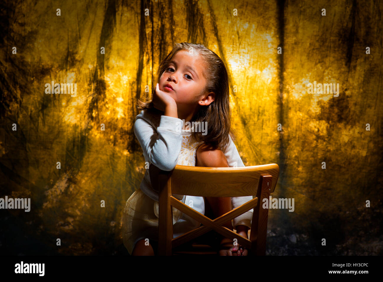 young girl in studio posing gold background sitting in chair looking ...