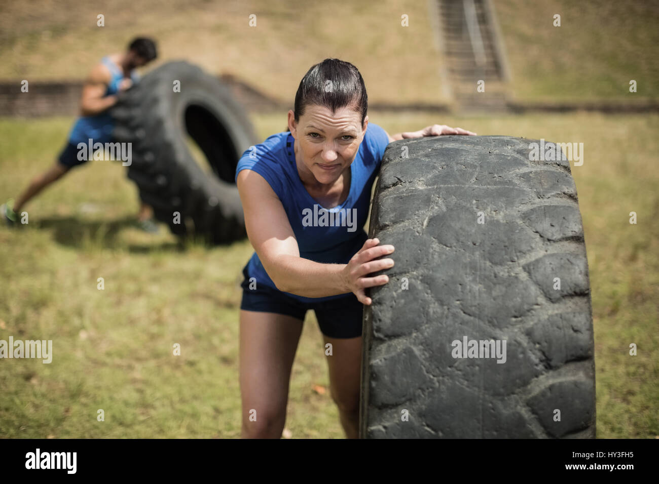 Fit woman flipping a tire during obstacle course in boot camp Stock ...