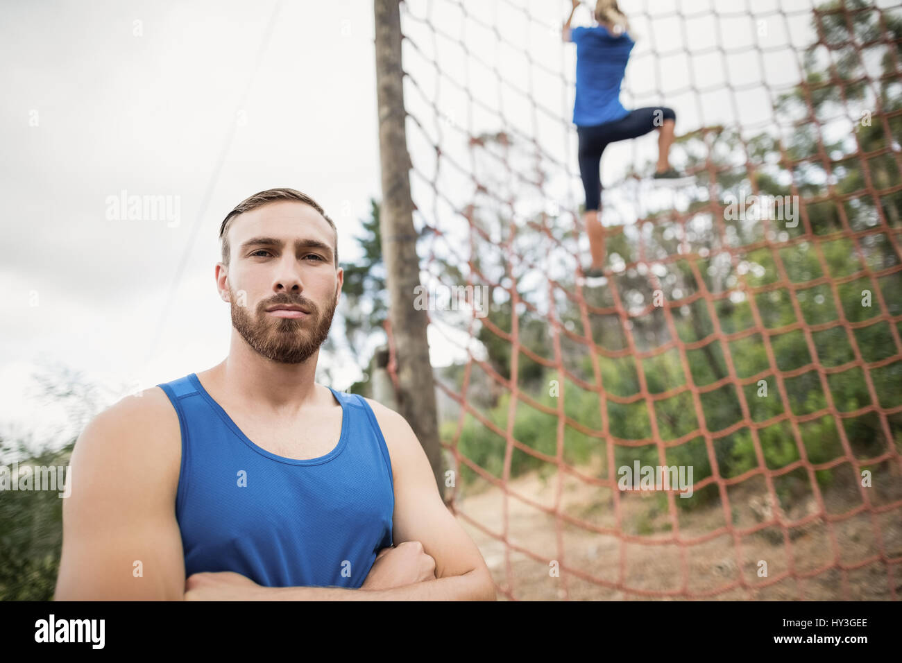 Woman climbing a net during obstacle course in boot camp Stock Photo ...