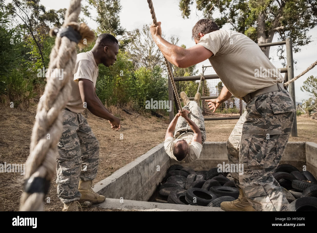 Young military soldiers practicing rope climbing during obstacle course ...