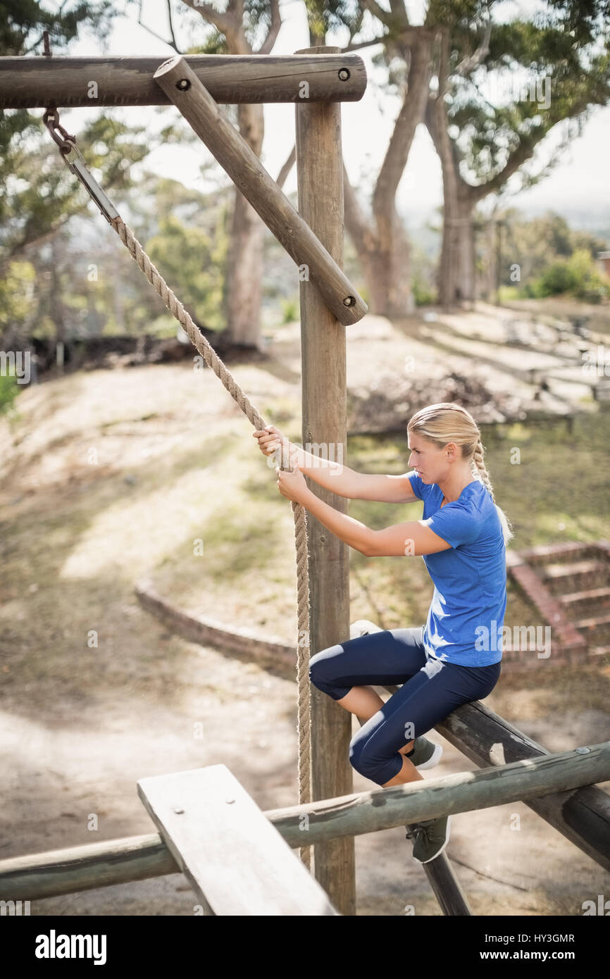 Fit woman climbing down the rope during obstacle course in boot camp ...